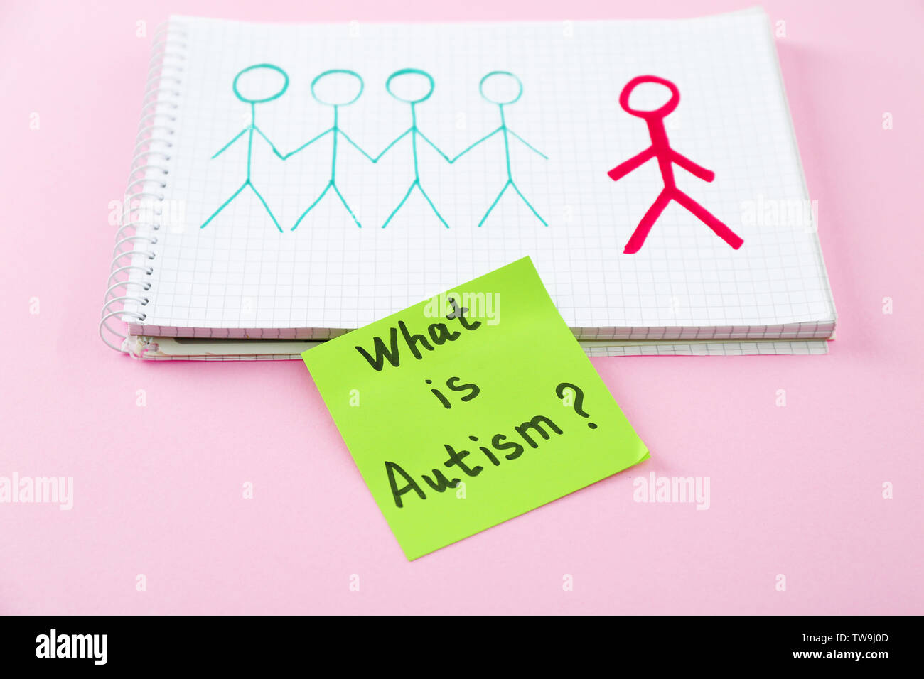 Paper with text WHAT IS AUTISM? and drawing in notebook on color ...