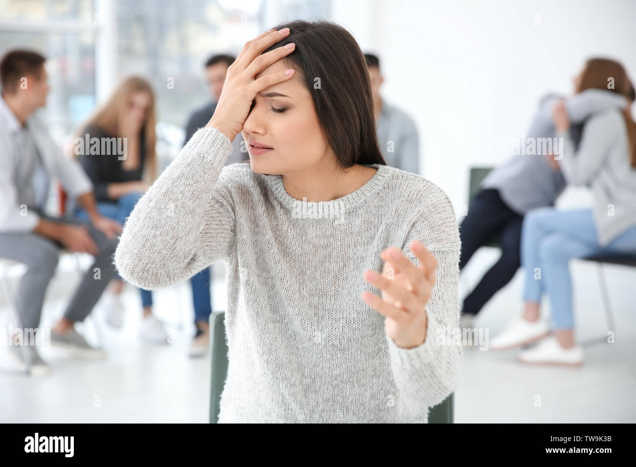 Stressed woman during group therapy, indoors Stock Photo - Alamy