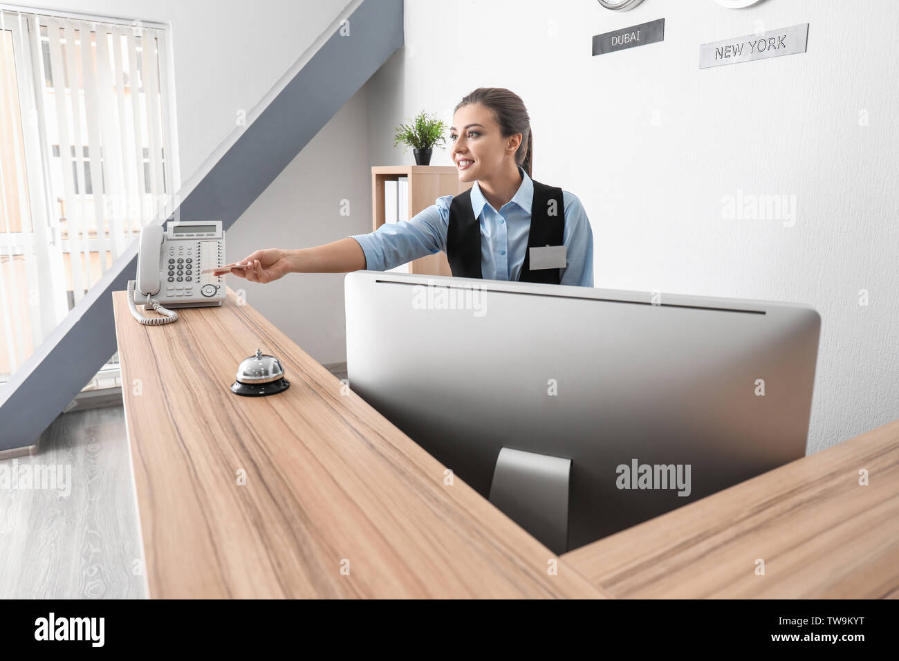 Female receptionist with card in hotel Stock Photo - Alamy