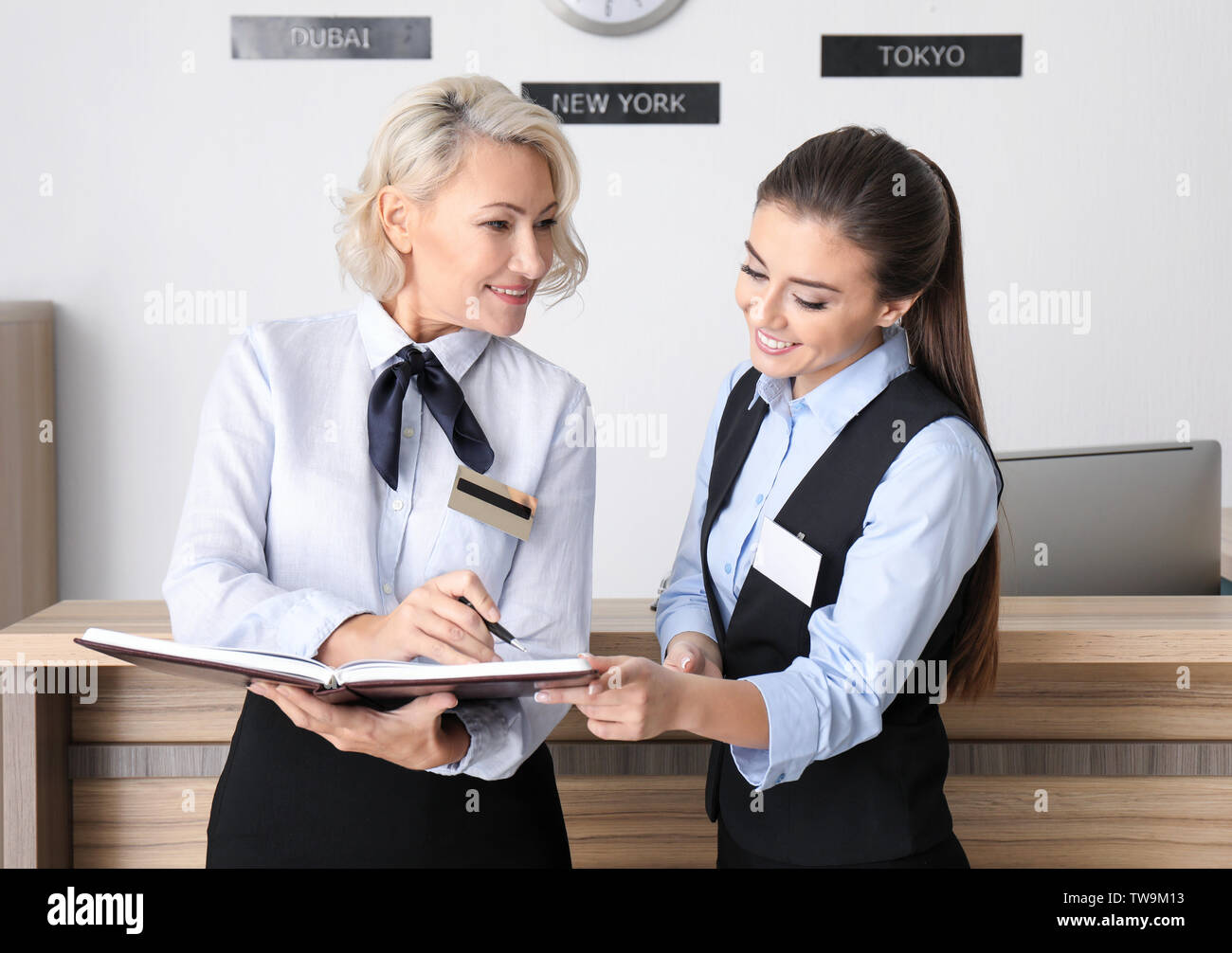 Female receptionist teaching trainee in hotel Stock Photo - Alamy