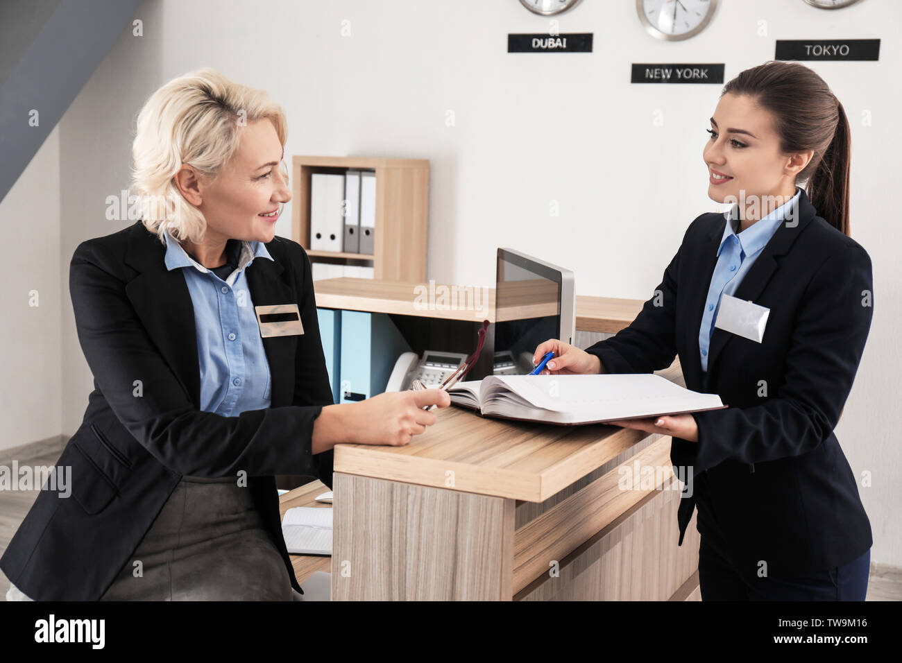 Female receptionist teaching trainee in hotel Stock Photo - Alamy