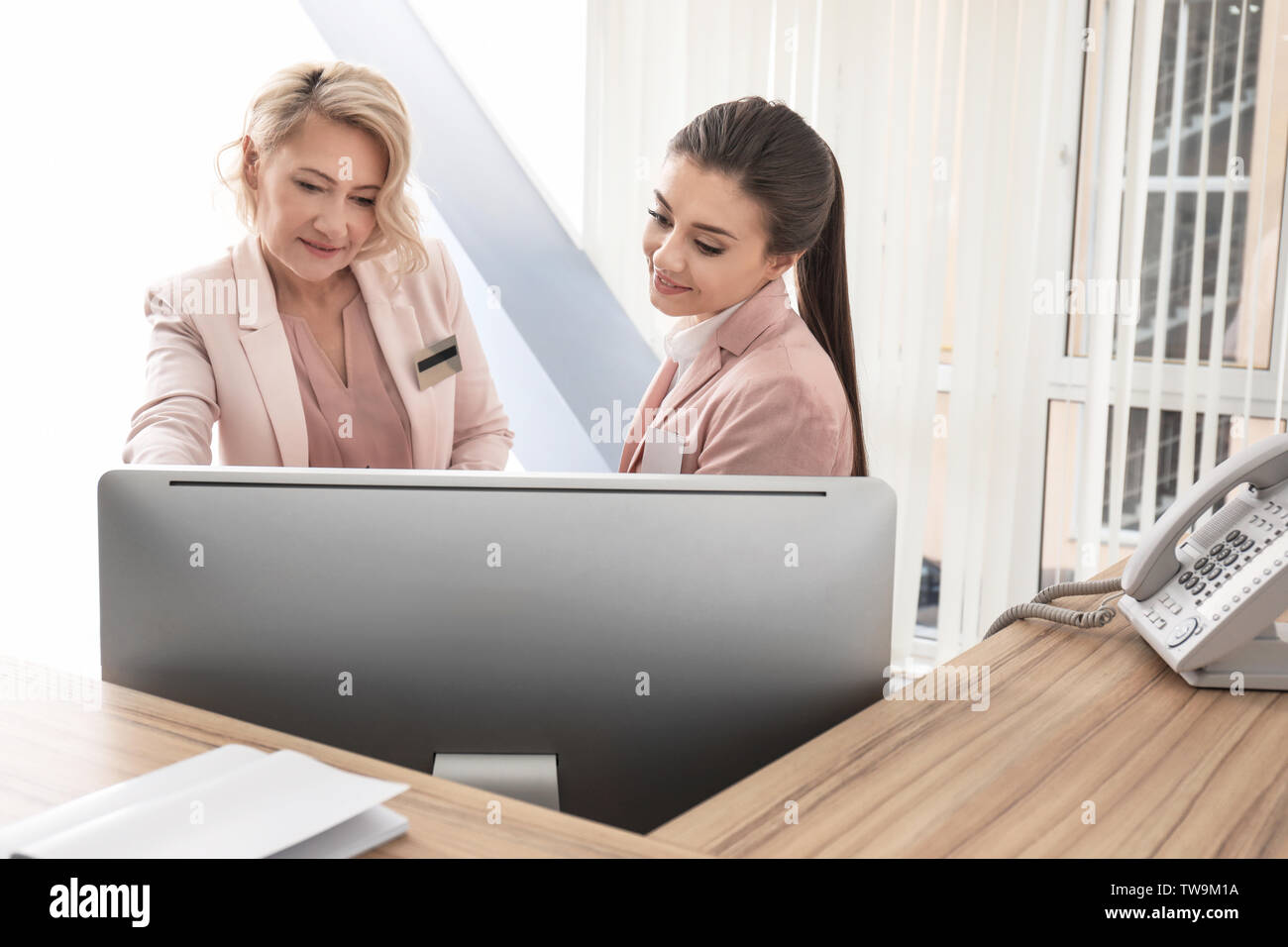 Female receptionist teaching trainee in hotel Stock Photo - Alamy