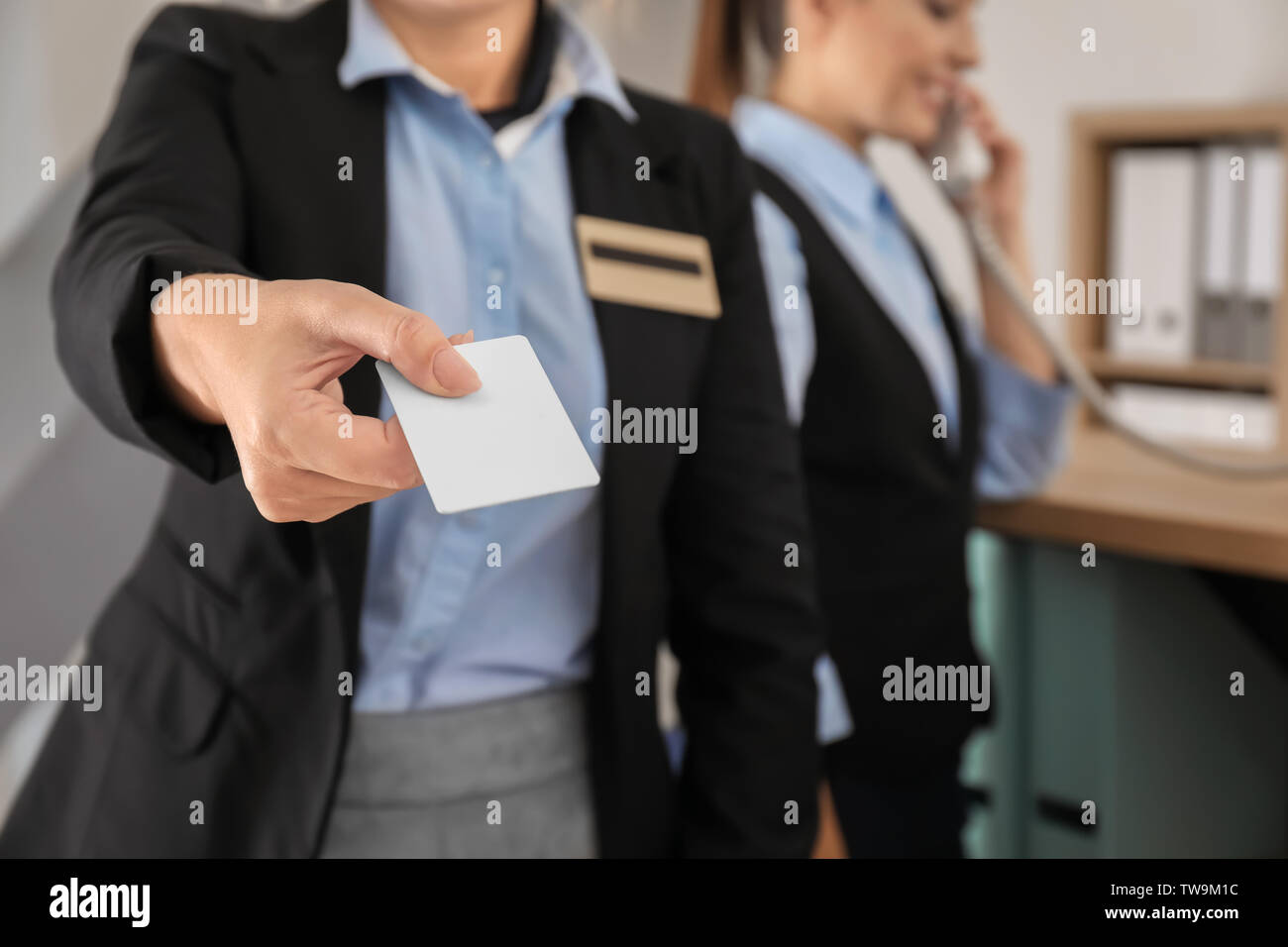 Female receptionist with card in hotel Stock Photo - Alamy