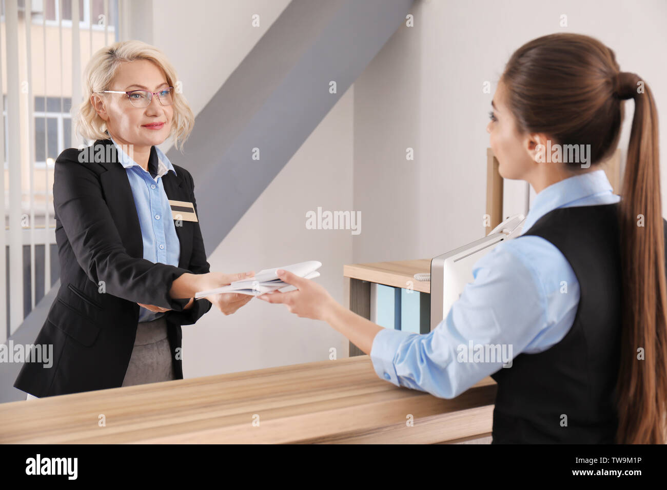 Female receptionist teaching trainee in hotel Stock Photo - Alamy