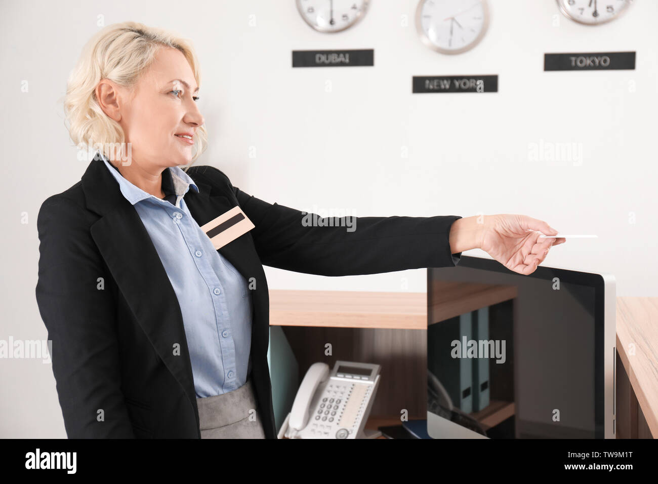 Female receptionist with card in hotel Stock Photo - Alamy