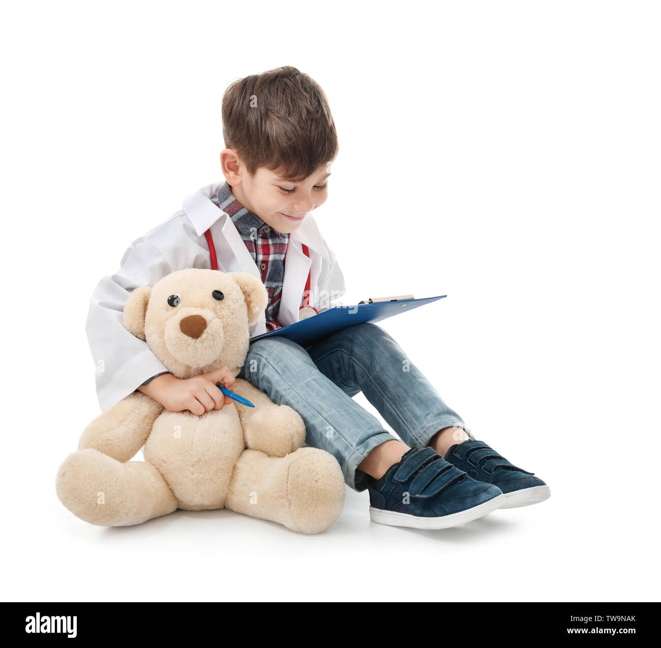 Cute little boy in doctor uniform with clipboard and toy bear on white ...