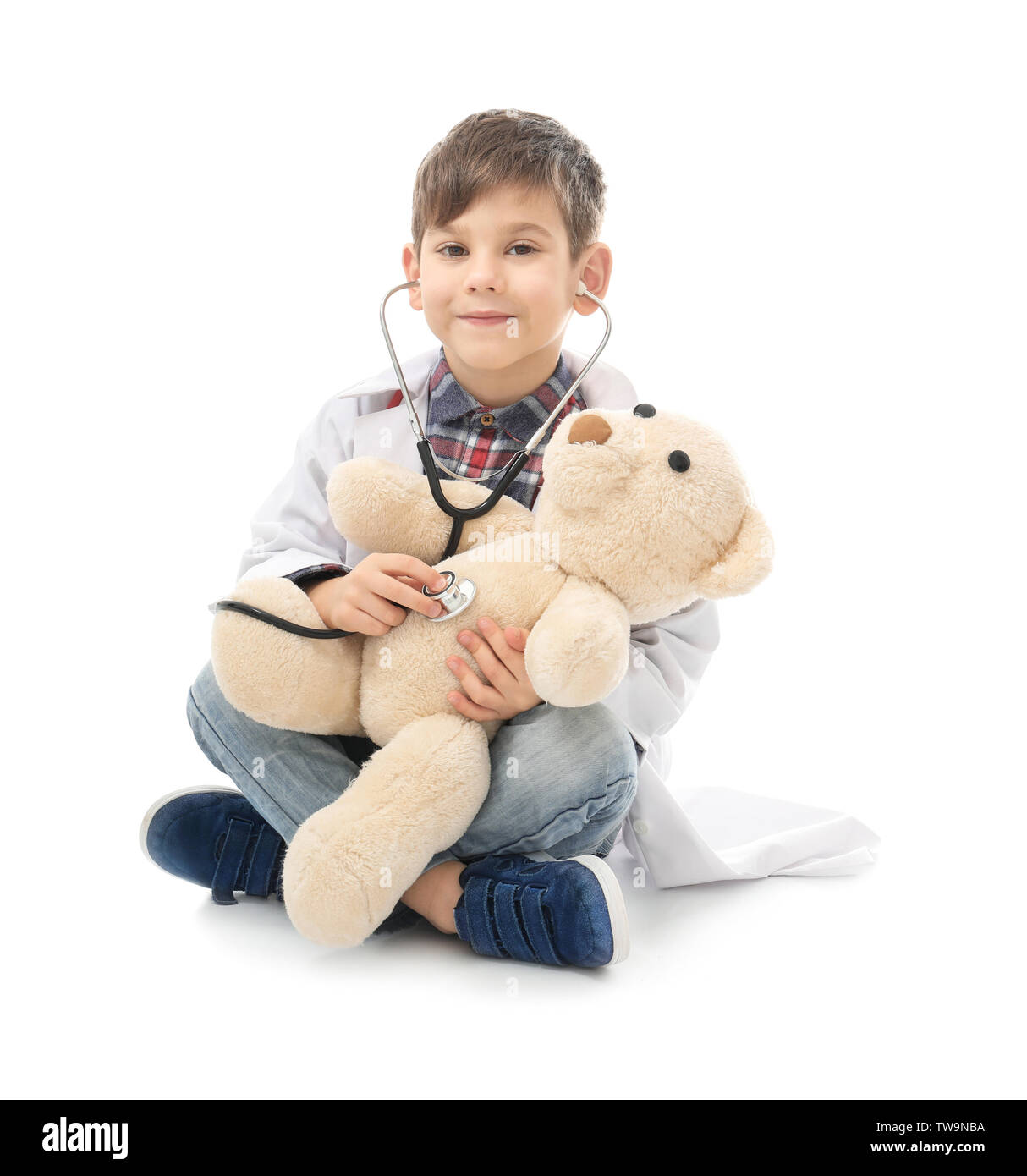 Cute little boy in doctor uniform playing with toy bear on white ...