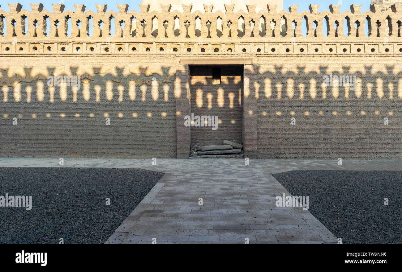 Stone bricks old decorated fence with wooden door and shadows of ...