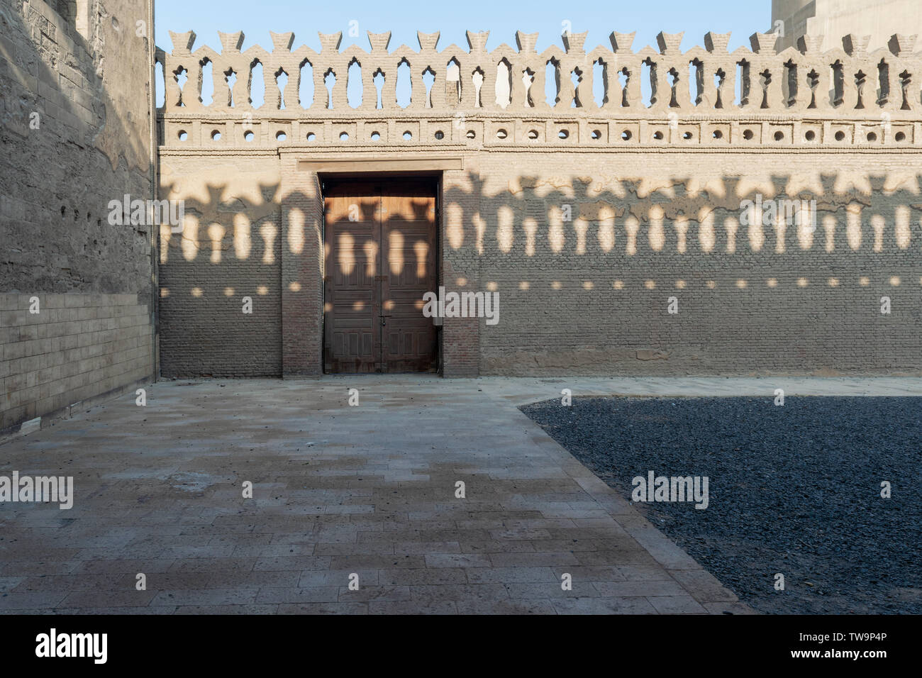 Stone bricks old decorated fence with wooden door and shadows of ...