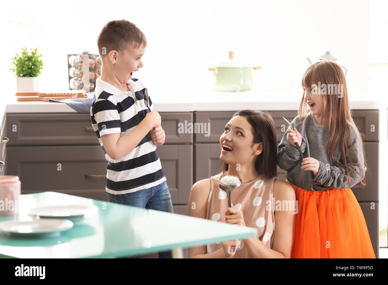 Happy family using utensils as microphone in kitchen Stock Photo - Alamy
