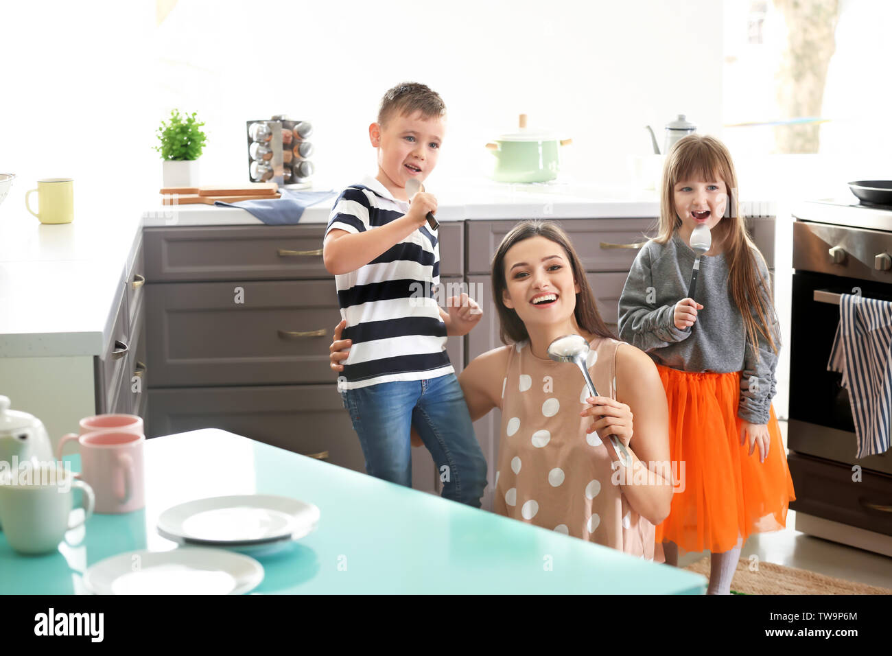 Happy family using utensils as microphone in kitchen Stock Photo - Alamy