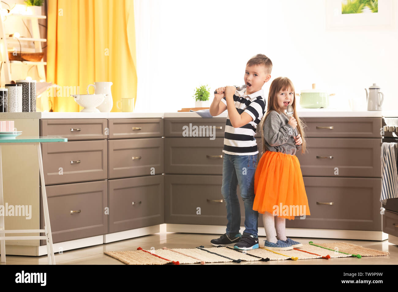 Cute little children using spoons as microphone in kitchen Stock Photo ...