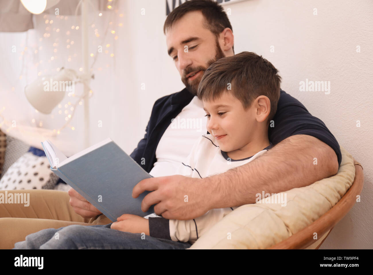 Cute little boy and his father reading book at home Stock Photo - Alamy