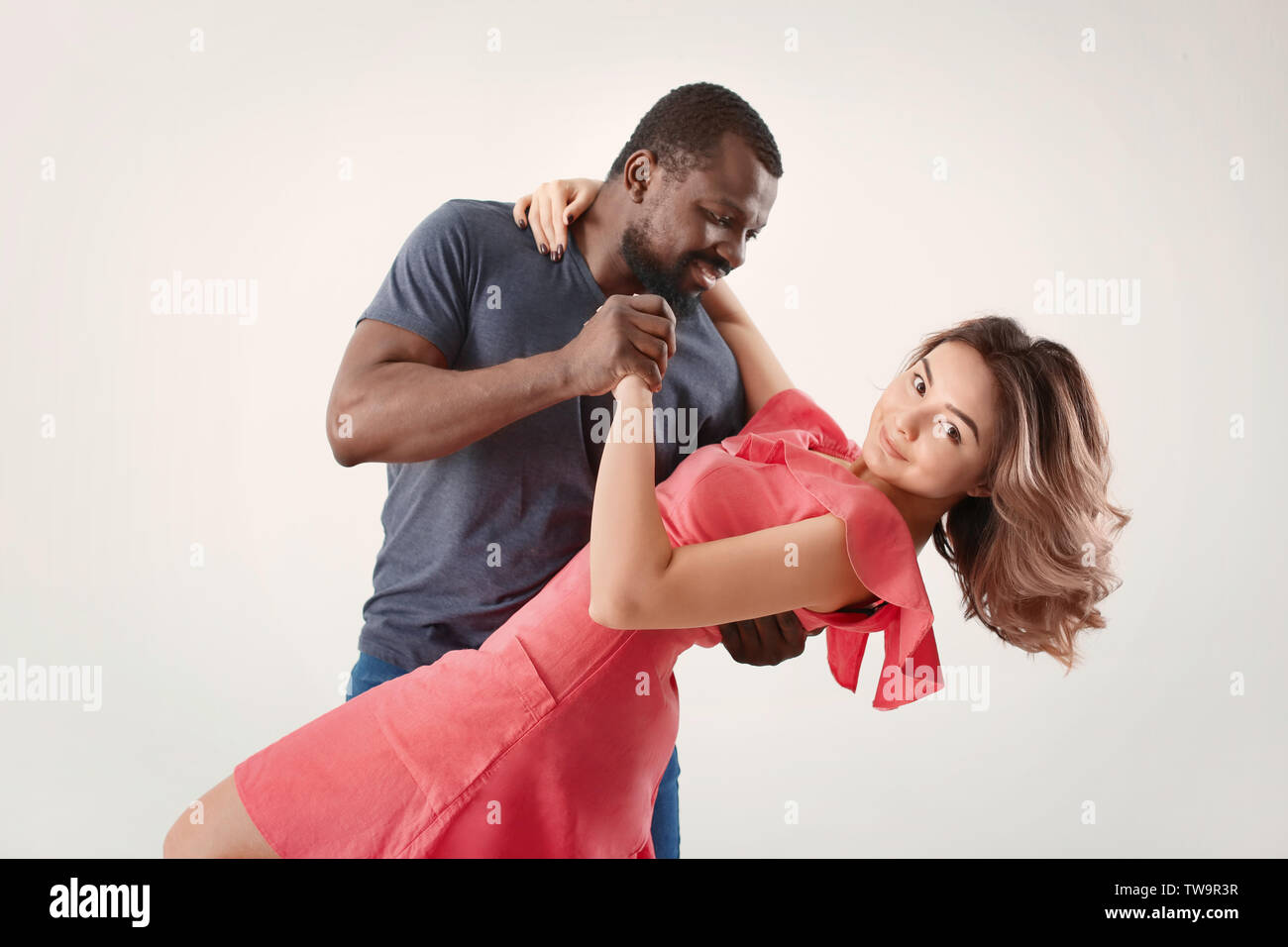 Cute interracial couple dancing against white background Stock Photo - Alamy