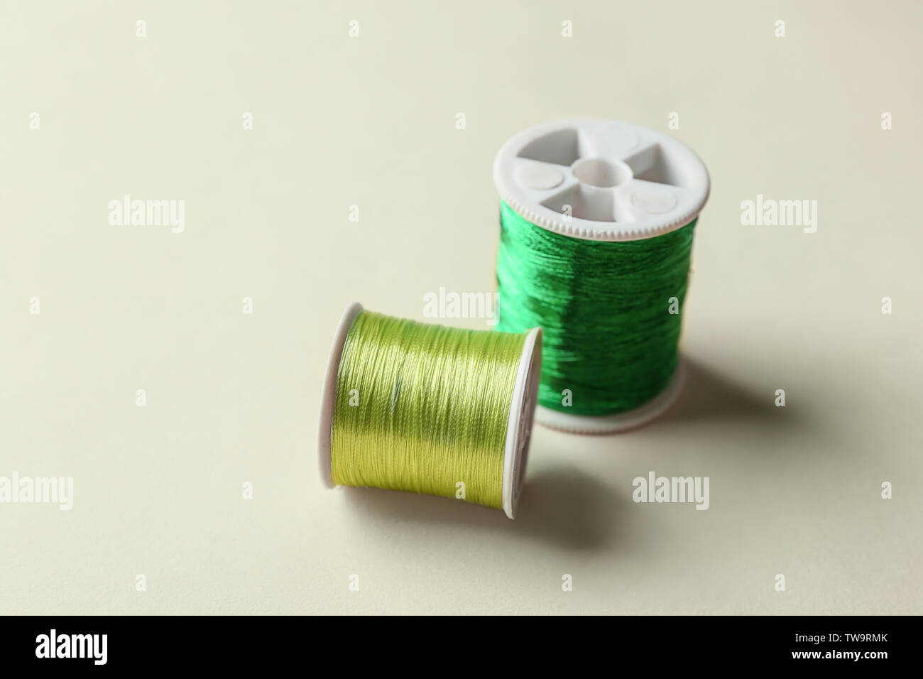 Green sewing threads on light background Stock Photo - Alamy
