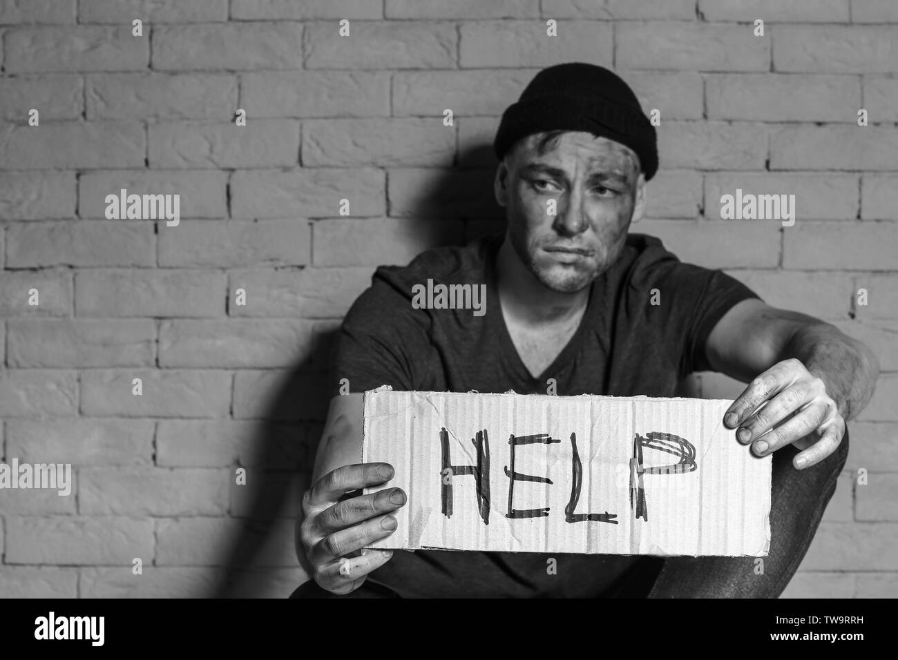 Homeless poor man holding carton board with word HELP while sitting ...