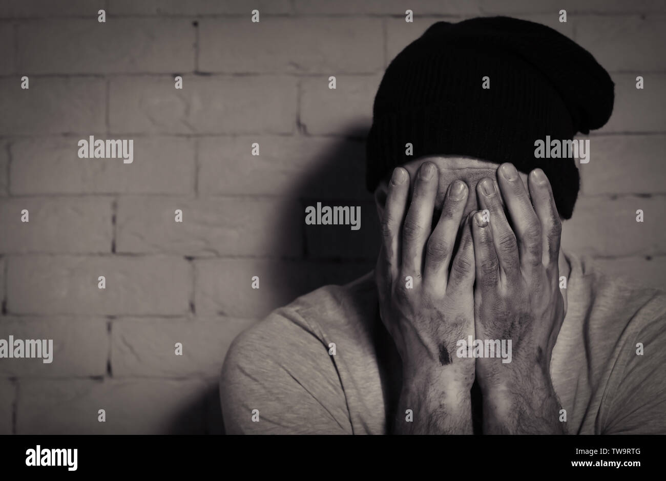 Hungry poor man crying near brick wall Stock Photo - Alamy