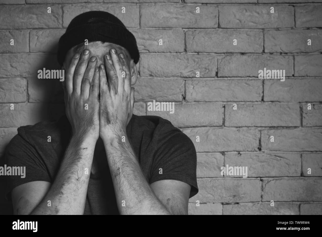 Hungry poor man crying near brick wall Stock Photo - Alamy