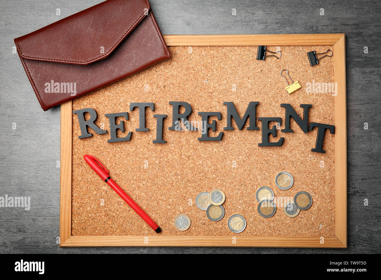 Cork board with word "Retirement", wallet and coins on grey background ...