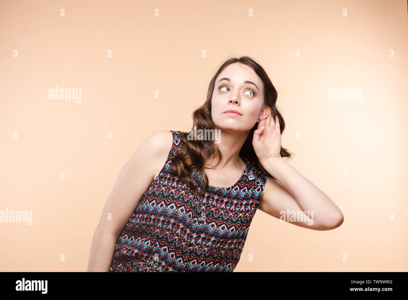Charming girl listening to gossips. Studio portrait of beautiful ...