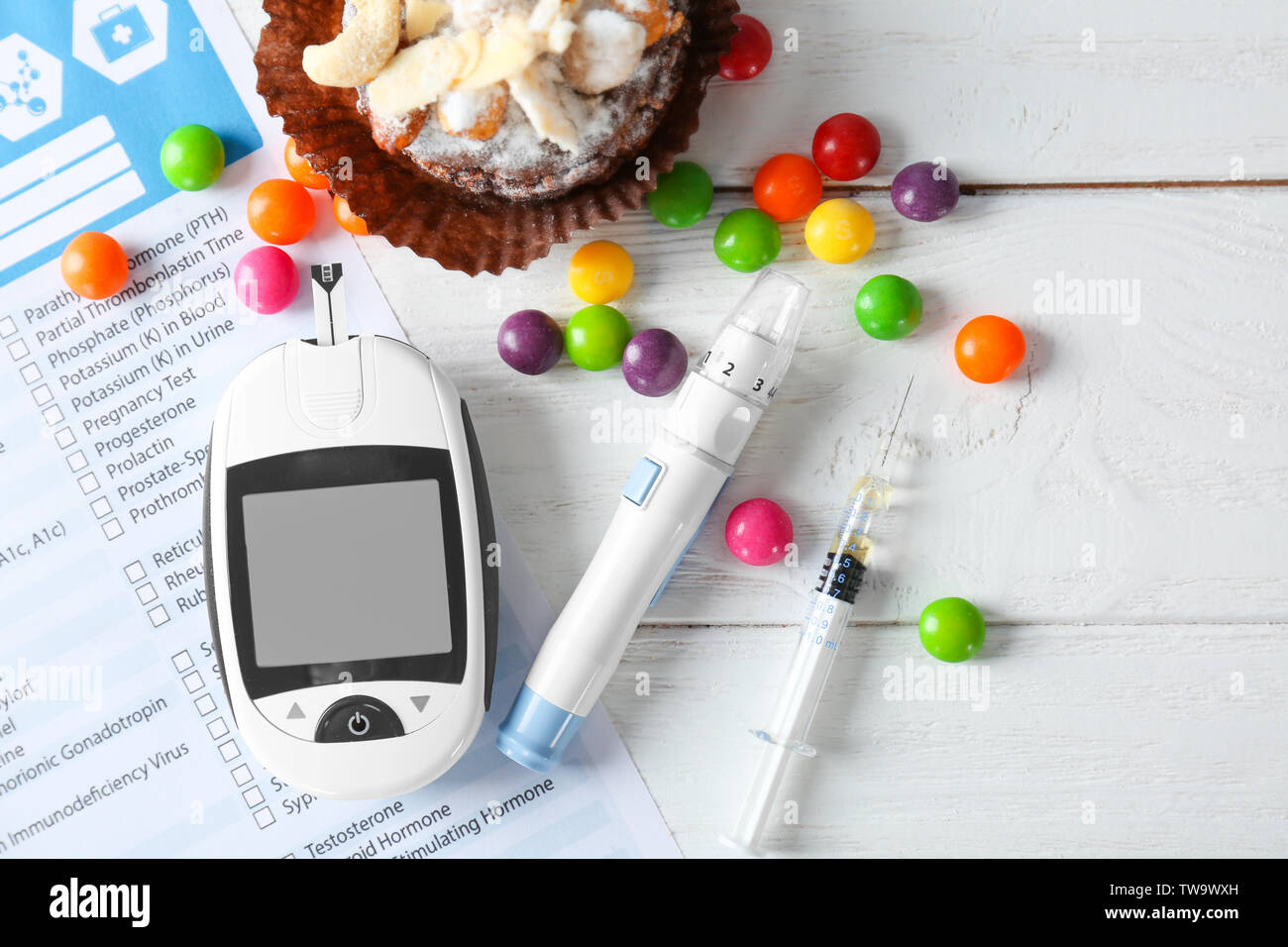 Digital glucometer, sweets and test form on table. Diabetes concept ...
