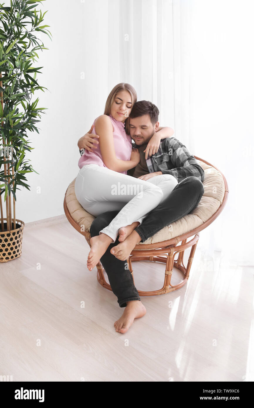 Cute young lovely couple sitting in armchair at home Stock Photo - Alamy