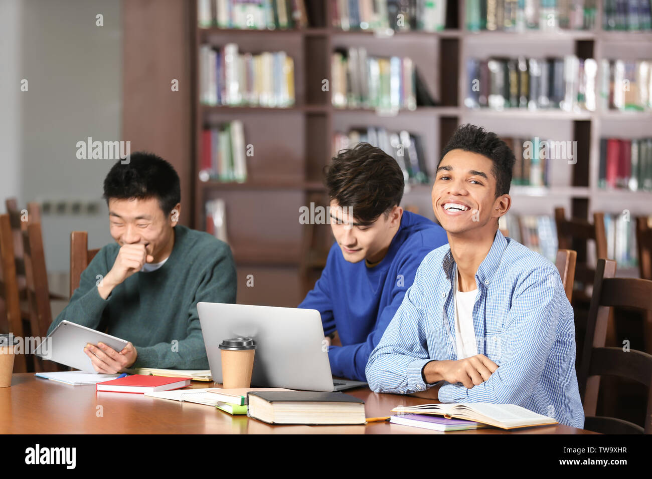Group of students studying at table in library Stock Photo - Alamy