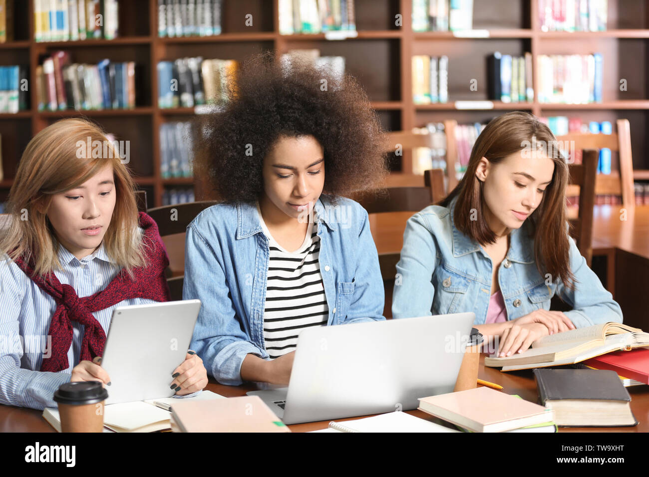 Group of students studying at table in library Stock Photo - Alamy