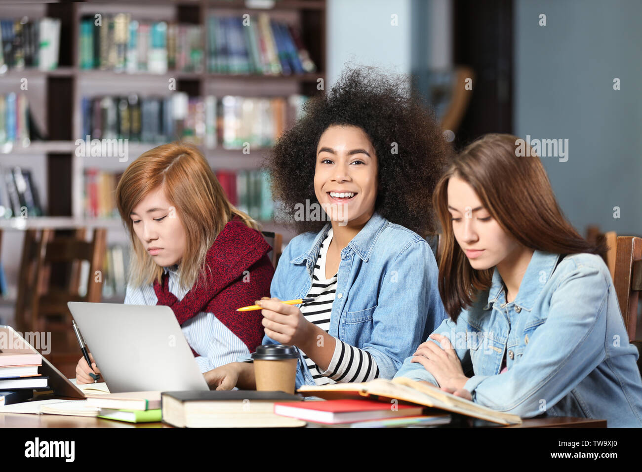 Group of students studying at table in library Stock Photo - Alamy