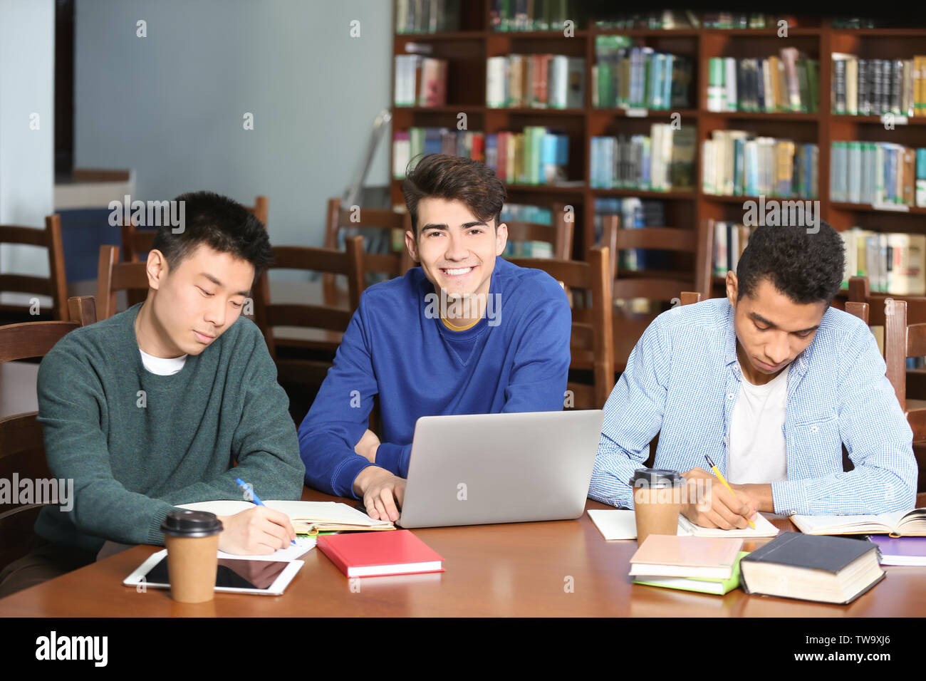 Group of students studying at table in library Stock Photo - Alamy