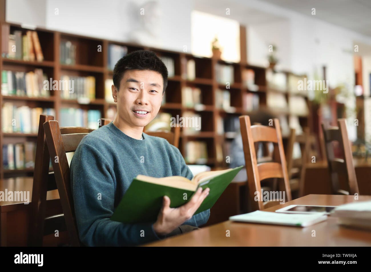 Asian student with book studying in library Stock Photo - Alamy