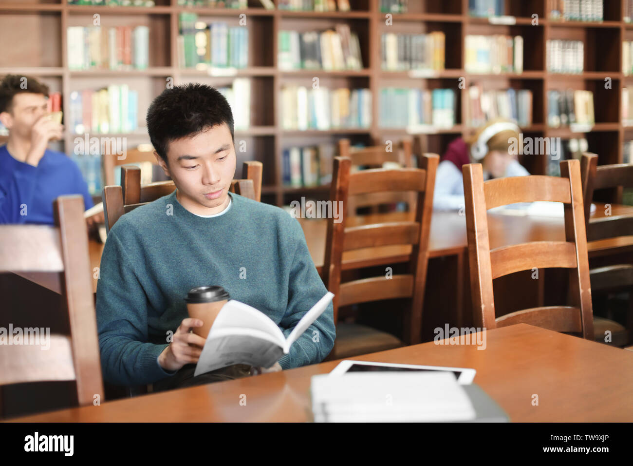 Asian student with book studying in library Stock Photo - Alamy