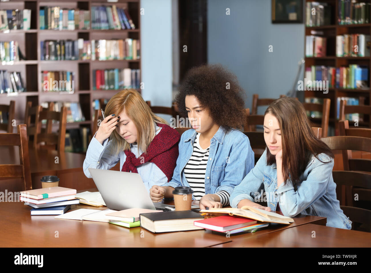 Group of students studying at table in library Stock Photo - Alamy
