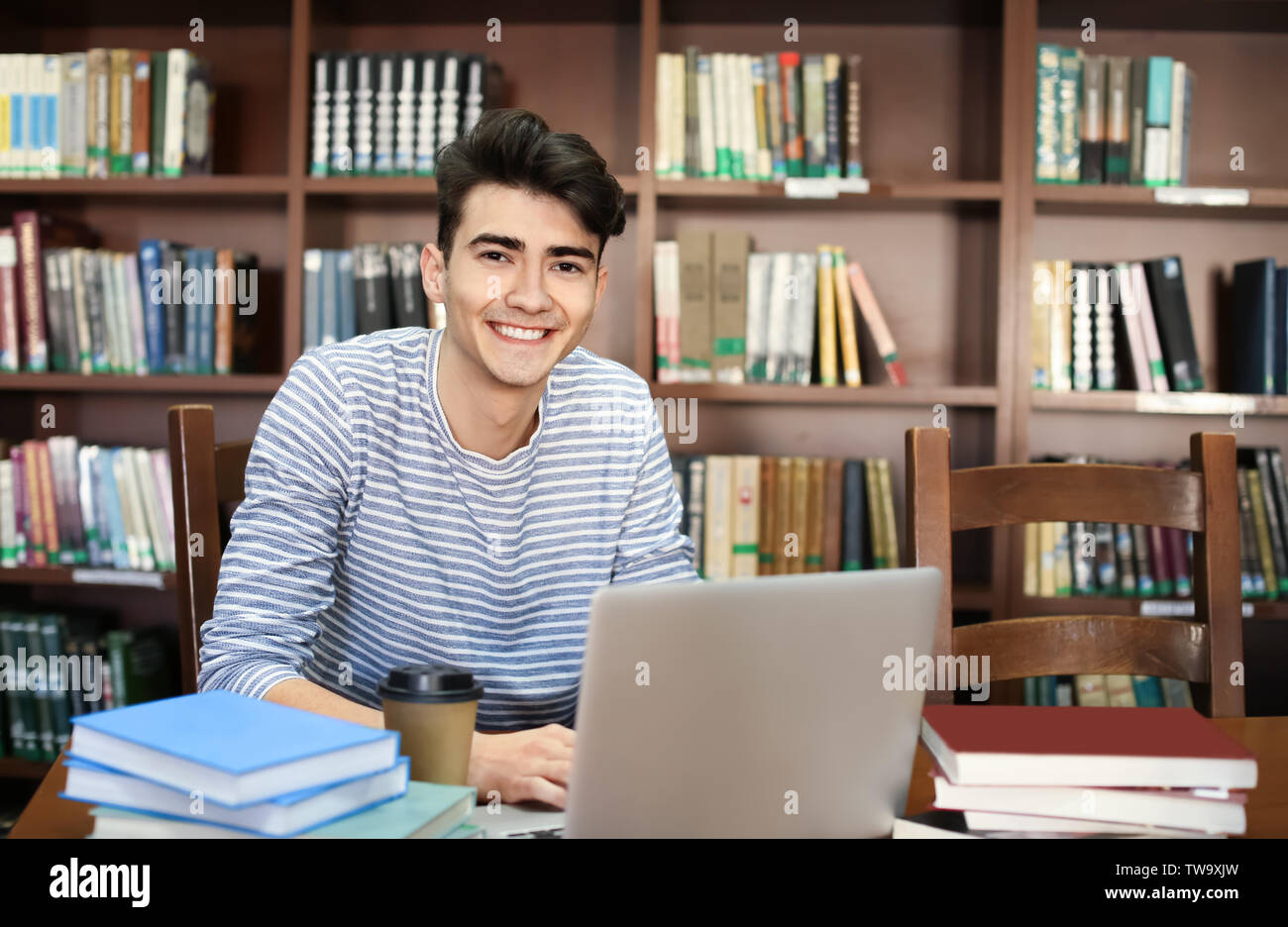 Student with laptop studying in library Stock Photo - Alamy