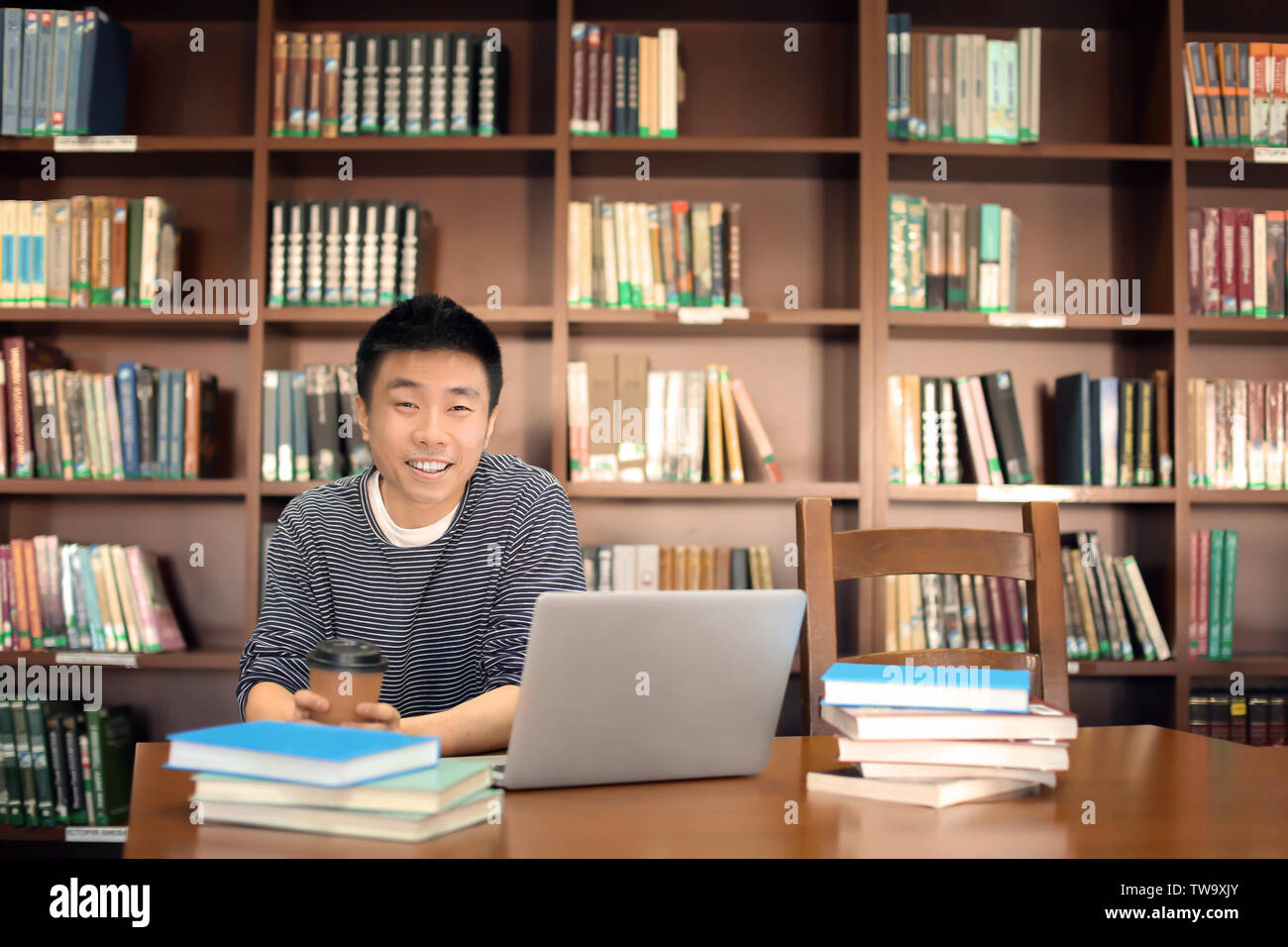 Asian student with laptop studying in library Stock Photo - Alamy