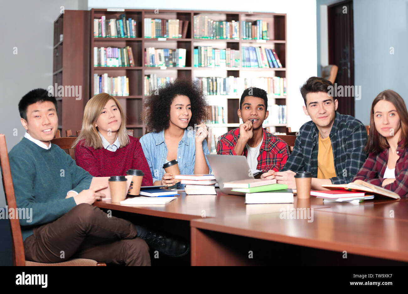 Group of students studying at table in library Stock Photo - Alamy