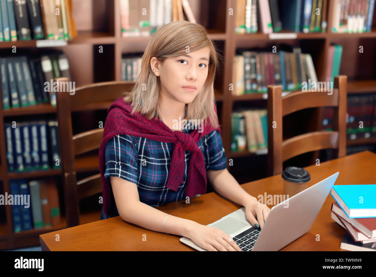 Asian student with laptop studying in library Stock Photo - Alamy
