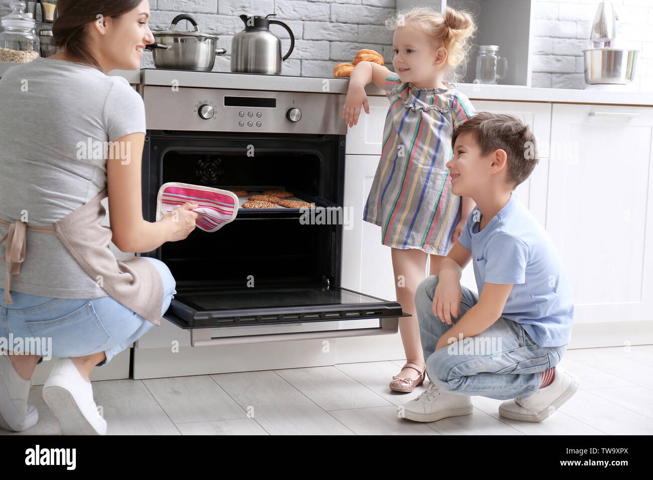 Little kids watching their mother bake cookies in oven indoors Stock ...