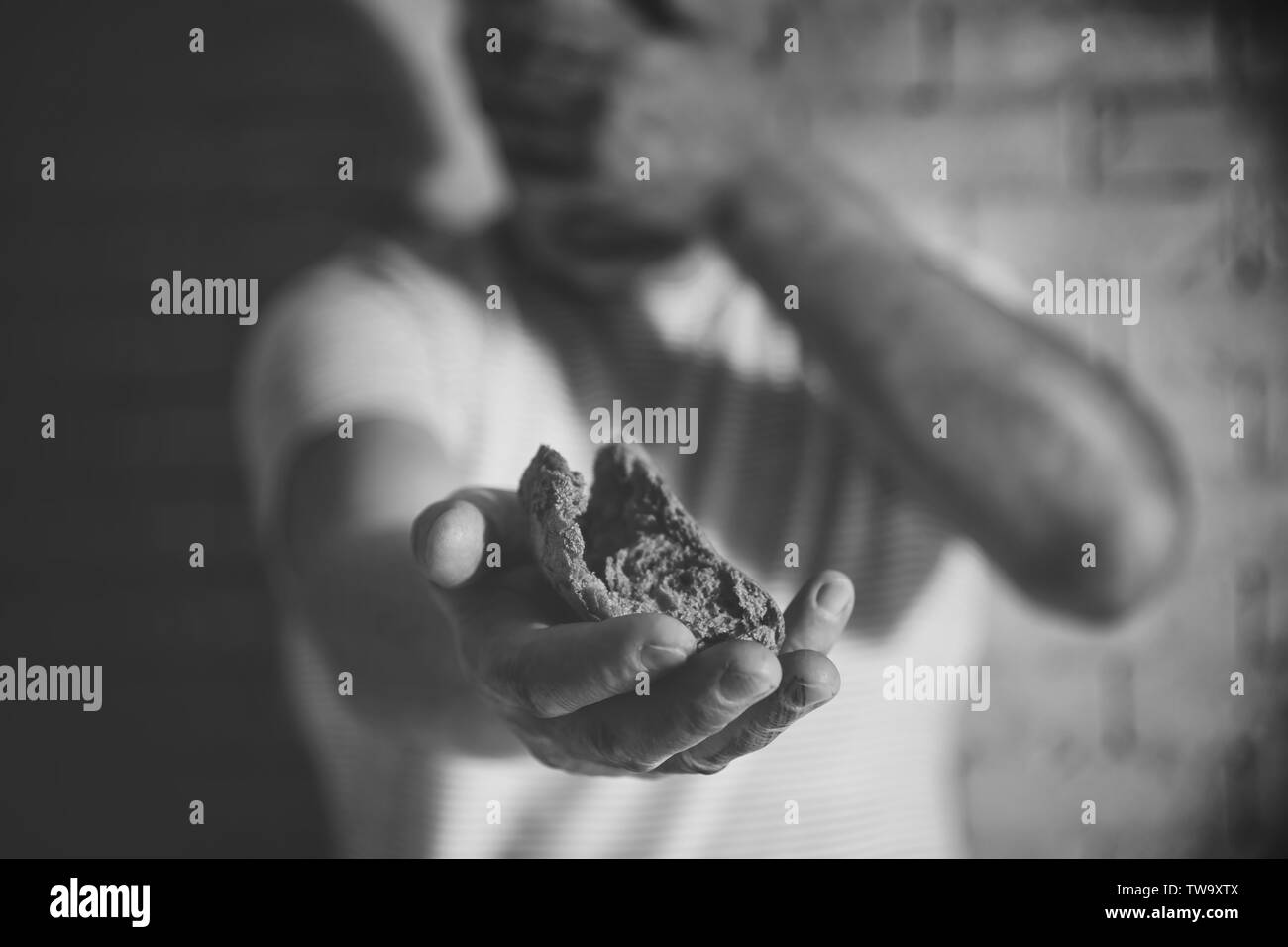 Poor man with little piece of bread, closeup. Black and white effect ...