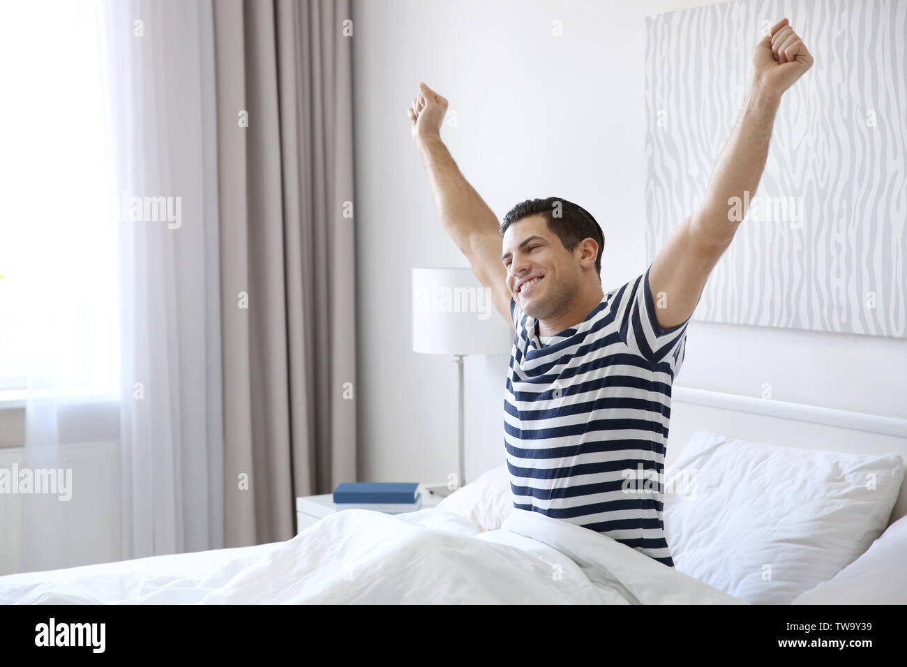 Young handsome man stretching in bed at home Stock Photo - Alamy