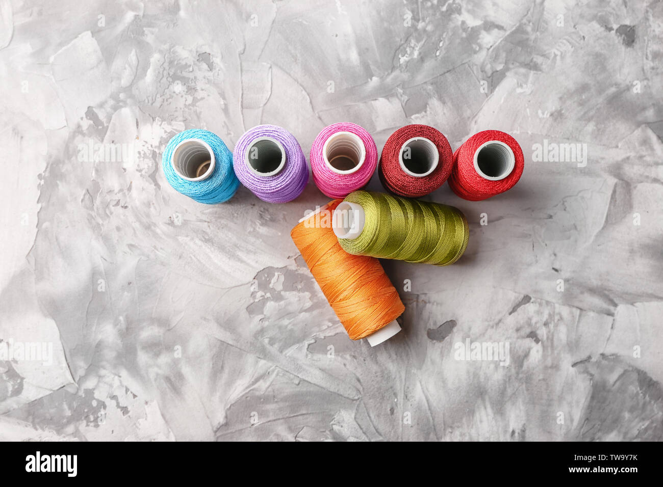 Colorful sewing threads on grey background Stock Photo - Alamy