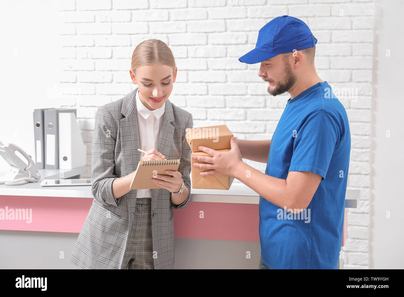 Female receptionist receiving parcels at workplace Stock Photo - Alamy