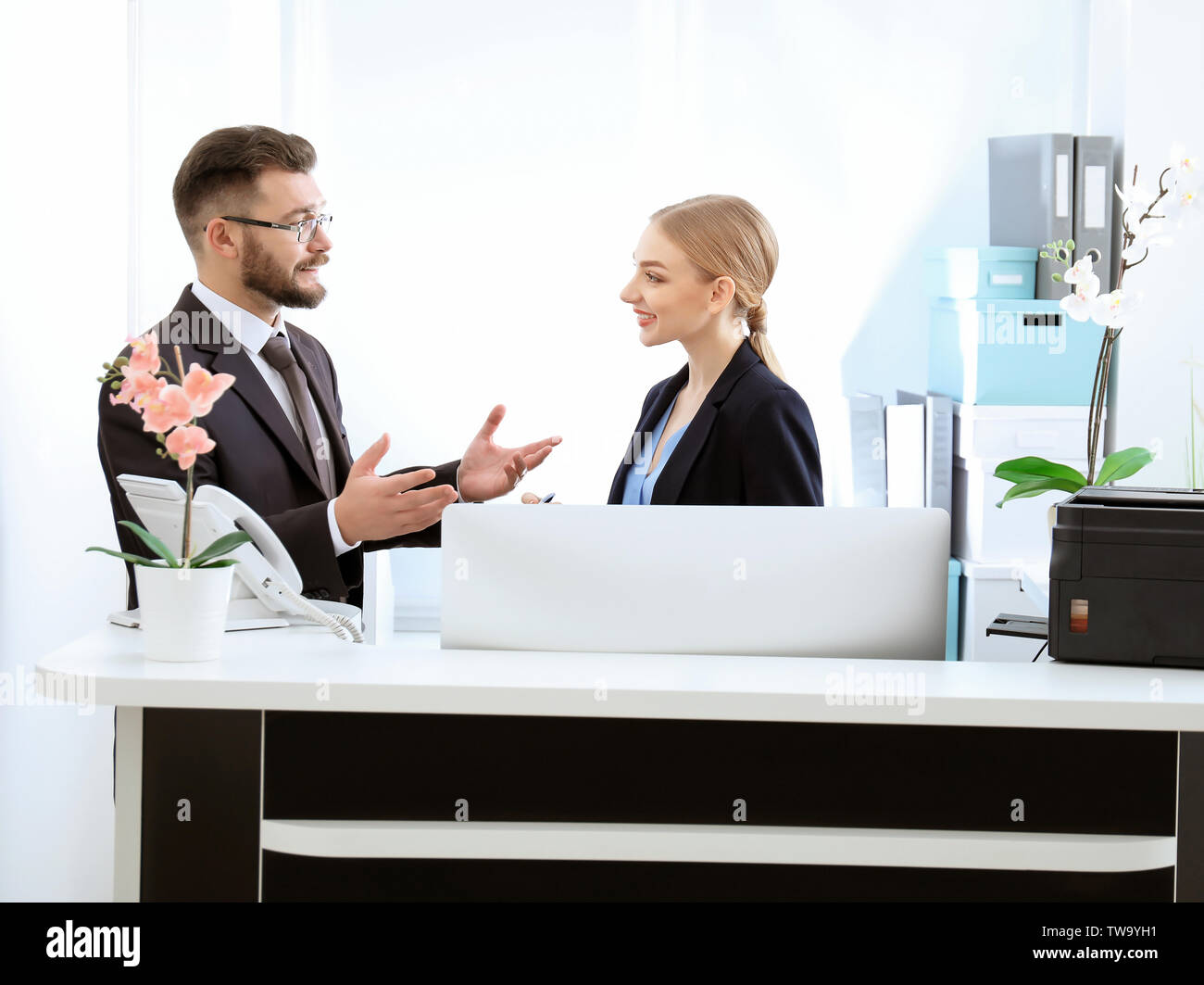 Male receptionist with trainee at workplace Stock Photo - Alamy
