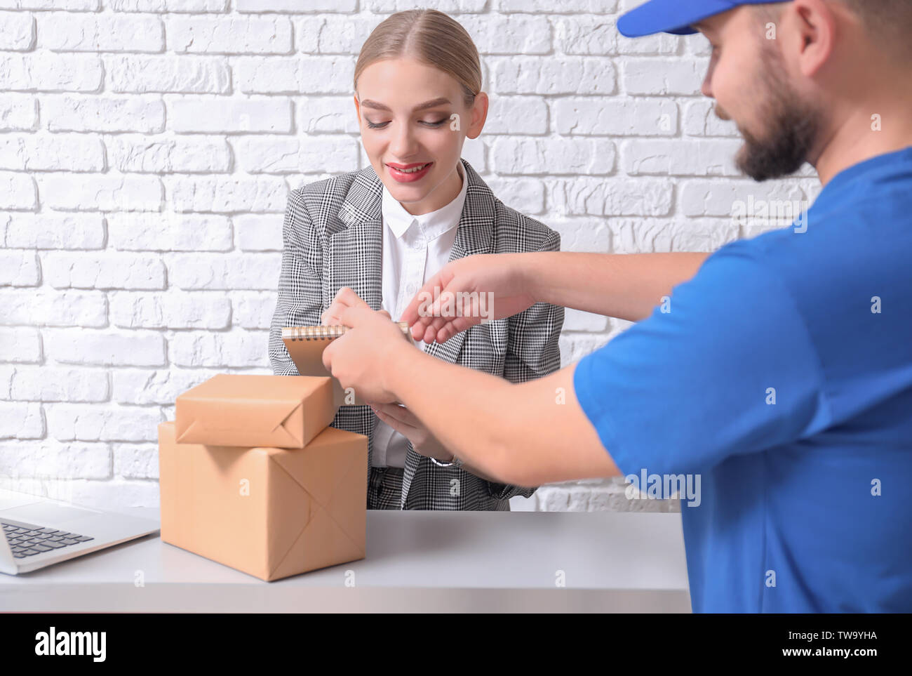 Female receptionist receiving parcels at workplace Stock Photo - Alamy