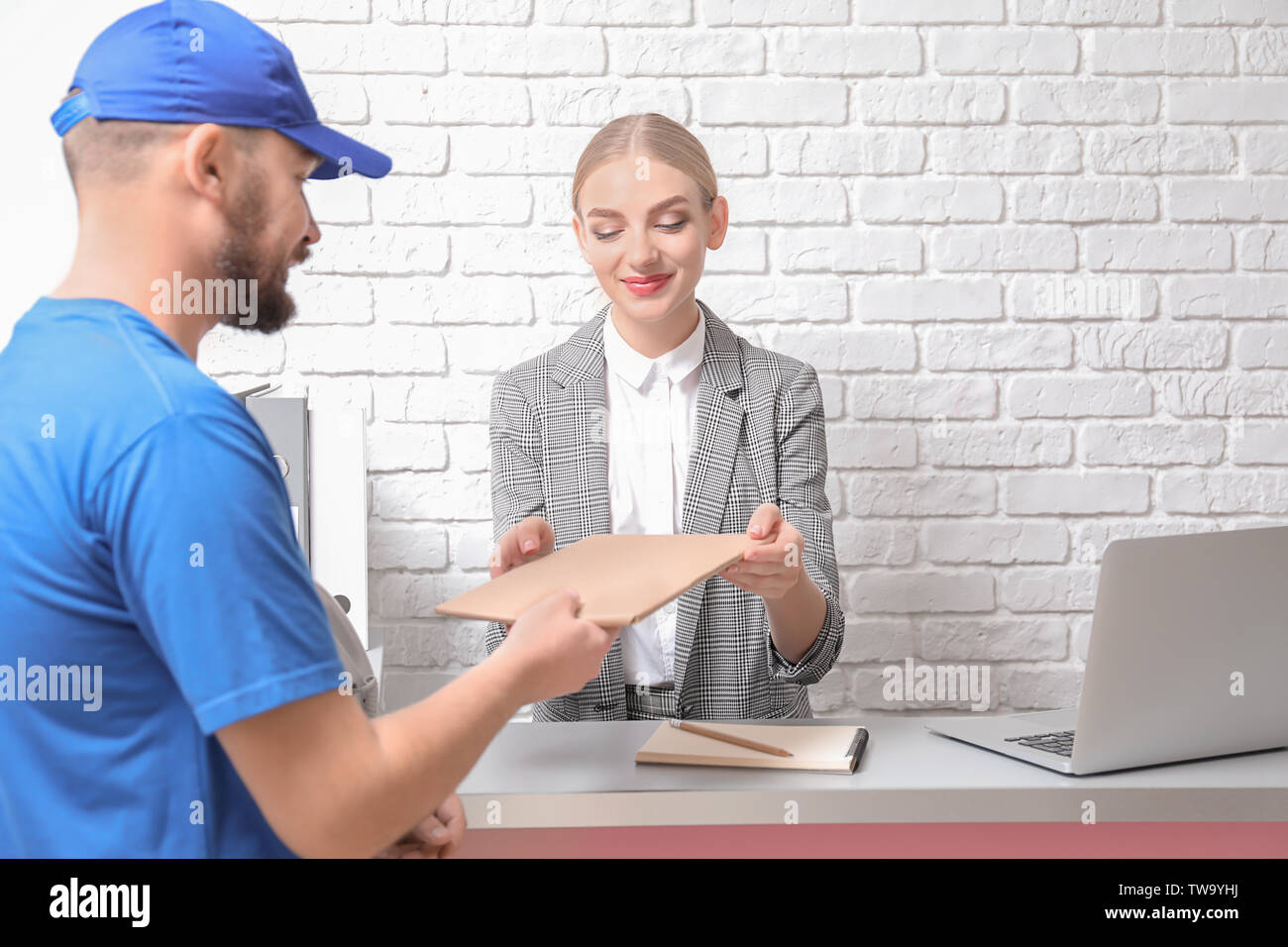 Female receptionist receiving parcel at workplace Stock Photo - Alamy