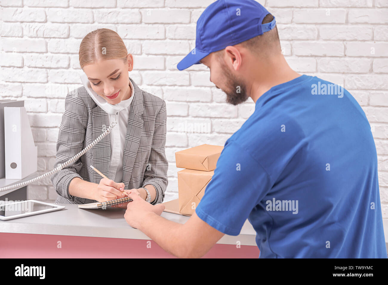 Female receptionist receiving parcels at workplace Stock Photo - Alamy