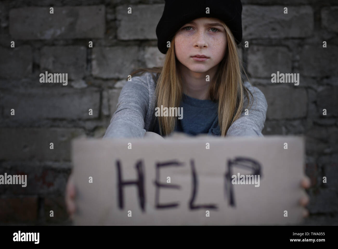 Homeless poor teenage girl holding piece of cardboard with word HELP ...