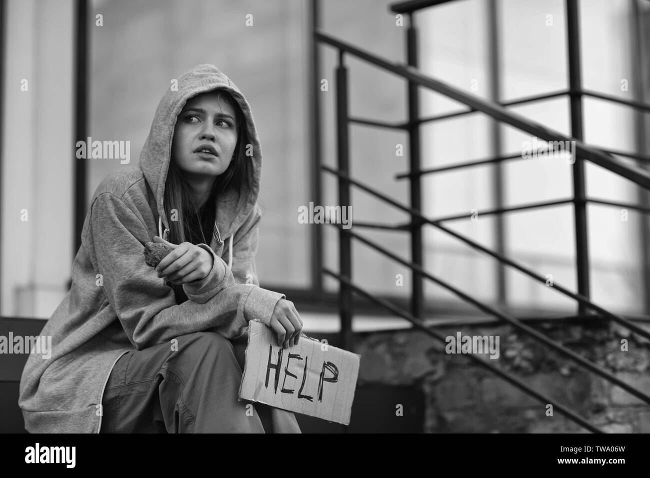 Homeless poor woman holding piece of cardboard with word HELP outdoors ...