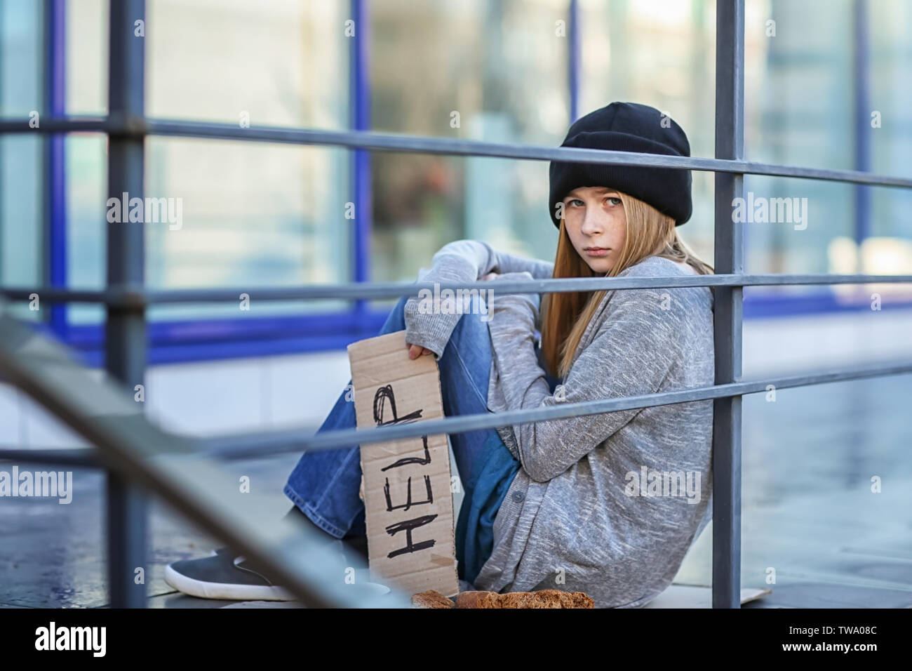 Homeless poor teenage girl holding piece of cardboard with word HELP ...