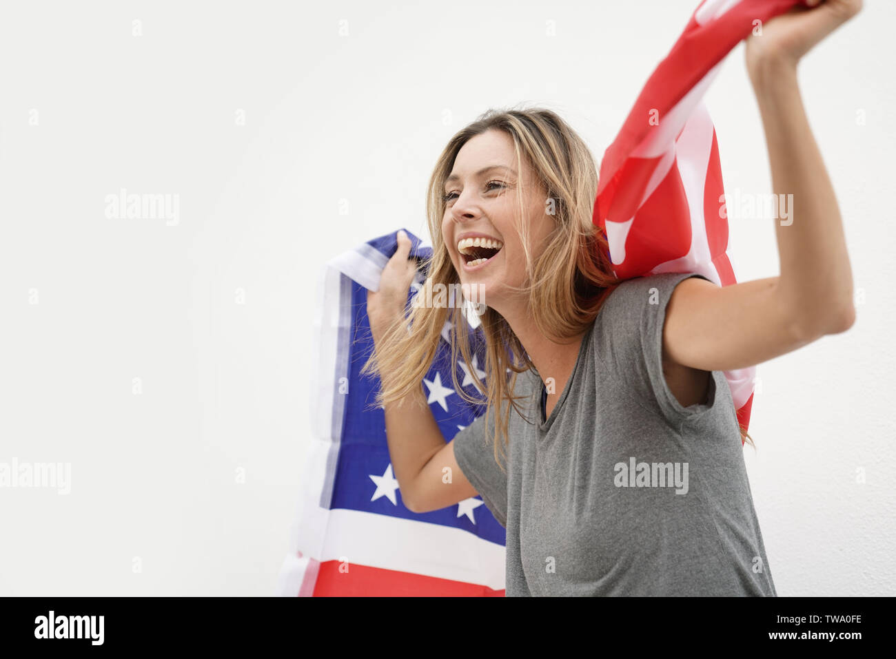 Gorgeous dynamic young woman smiling with big American flag on white ...